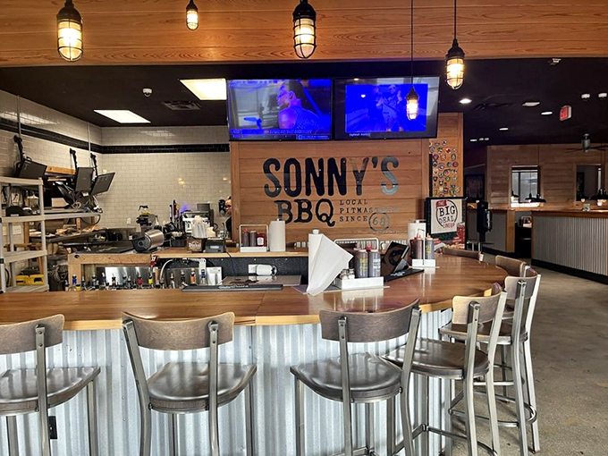 The bar area offers front-row seats to the barbecue action, where wood-paneled walls and industrial lighting set the stage for meat-centric magic.