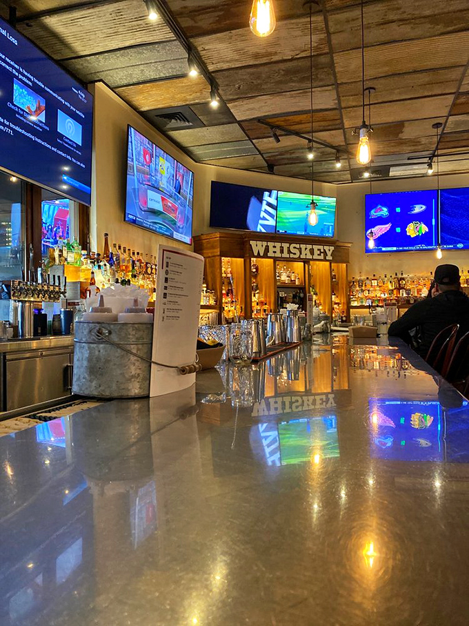 The bar gleams like a whiskey wonderland, where bottles stand at attention and Edison bulbs cast a glow that makes everyone look like they've made excellent life choices.