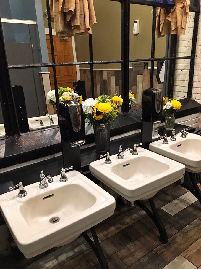 Even the restroom maintains the rustic-industrial charm, with fresh flowers adding a touch of unexpected elegance to the barbecue experience.