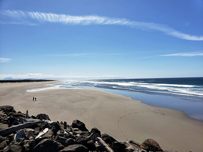 Miles of pristine beach where two figures demonstrate the proper way to feel insignificant against nature's grandeur. Soul-cleansing views included at no extra charge.