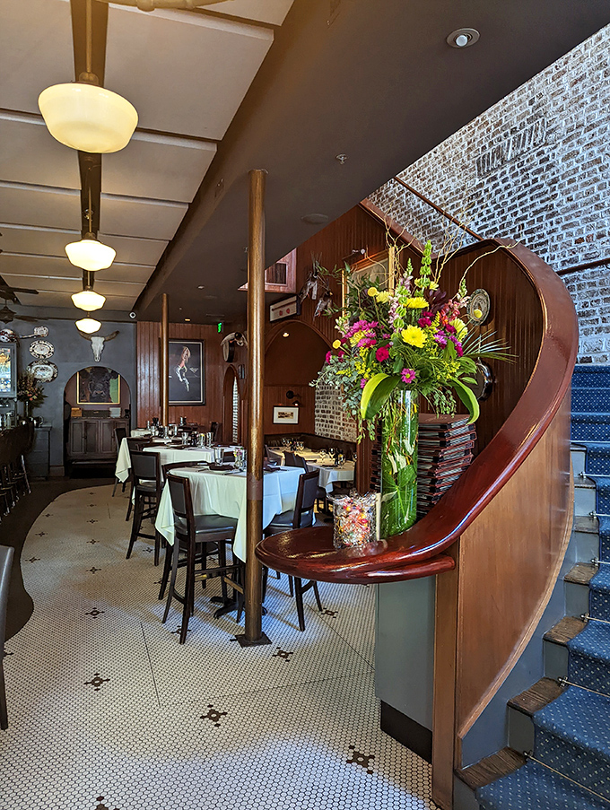 The staircase curves like a question mark leading upstairs, while fresh flowers stand guard over tables of anticipation.