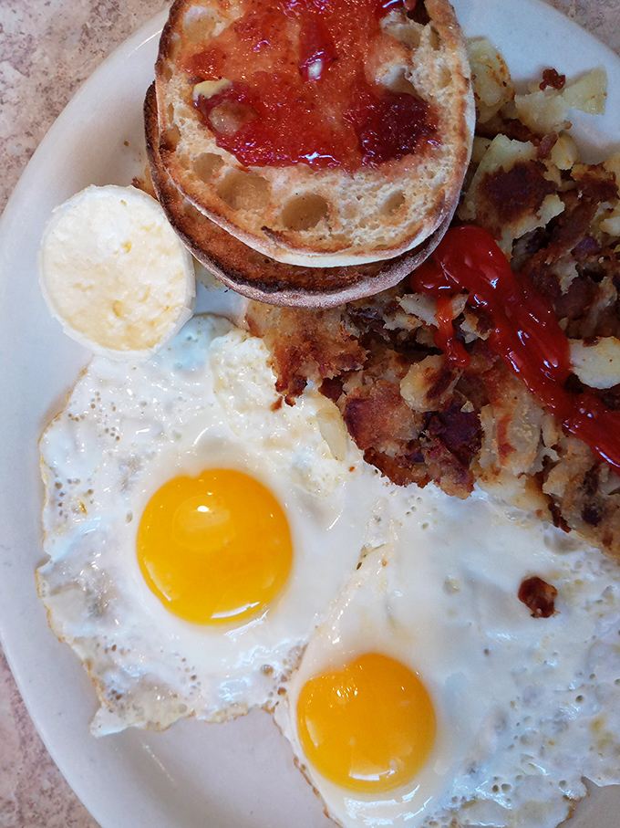 The breakfast platter that answers the eternal question: "Why choose?" Two sunny eggs, crispy potatoes, and toast ready for jam application.