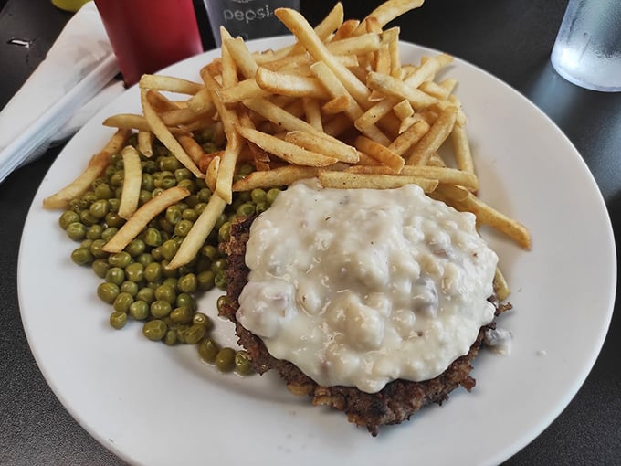 Country-fried steak swimming in peppery gravy, with fries and peas standing by. This isn't just lunch&mdash;it's the reason elastic-waist pants were invented.