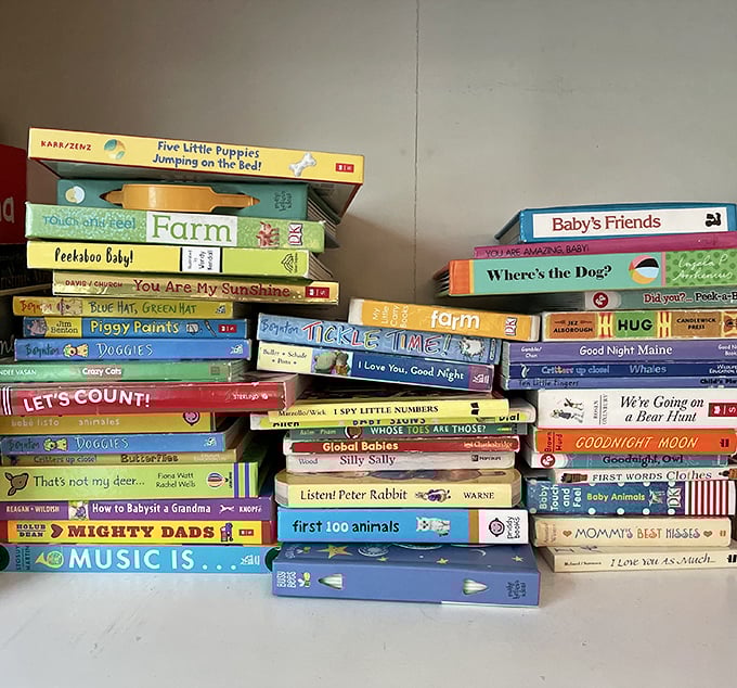 Children's books stacked higher than a toddler's ambitions. "Mighty Dads" and "Music Is..." waiting to create new bedtime memories.