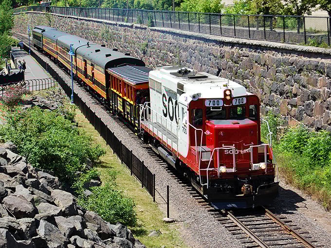 Stone walls cradle the tracks as this colorful locomotive navigates a corridor carved between Minnesota's natural rock formations.