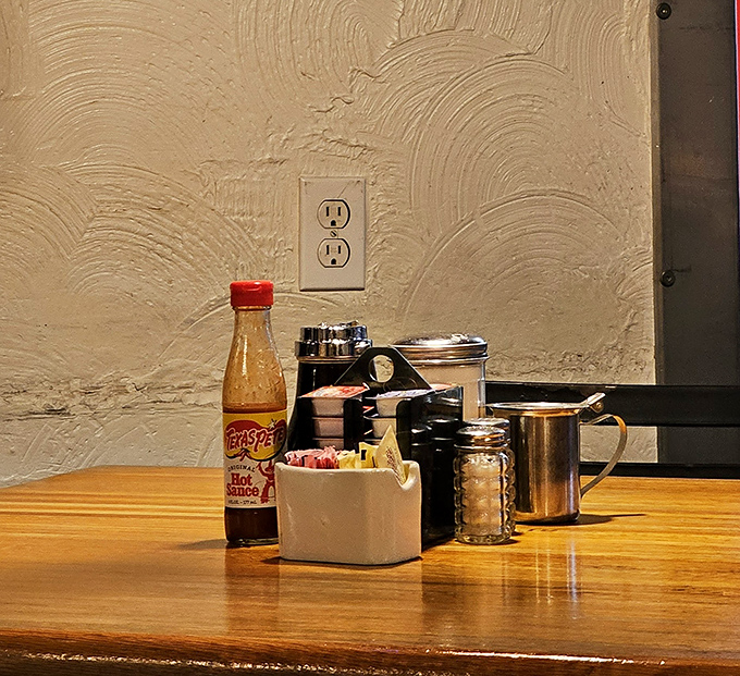 Table essentials arranged with military precision—hot sauce, sweeteners, and condiments standing at attention, ready for your breakfast battle plan.