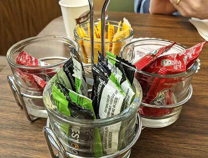The condiment caddy&mdash;organized like a tiny United Nations of flavor. Those little packets hold the power to customize your experience.
