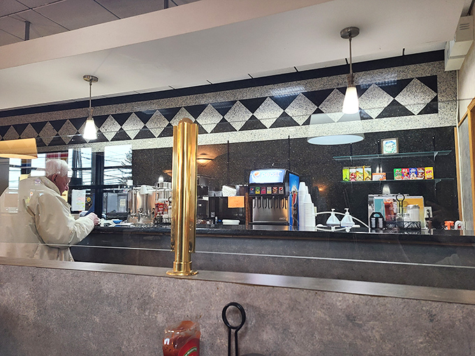 The counter where coffee cup bottomless pits are filled without judgment. Morning rituals performed with quiet dignity.