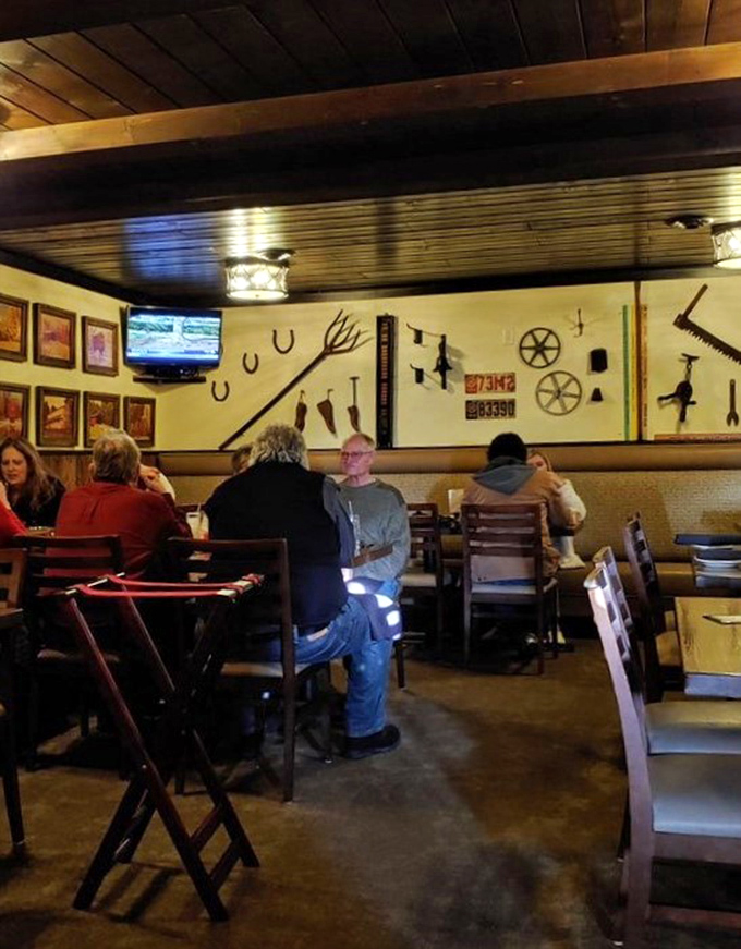 Diners settle into the comfortable embrace of ladder-back chairs, surrounded by farm tools that once tilled the very land that produced their dinner.