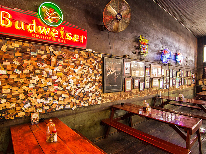 Neon beer signs illuminate walls darkened by decades of smoke. Those business cards aren't decoration&mdash;they're a community built one brisket at a time.