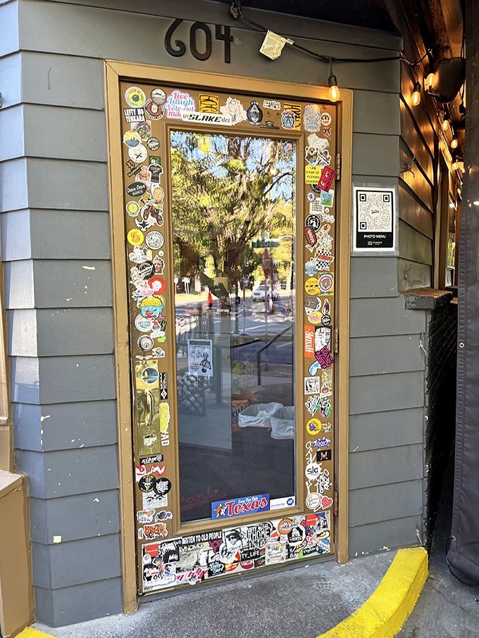 The entrance door, framed with stickers and mementos, stands as a colorful guestbook of visitors who came hungry and left as evangelists.