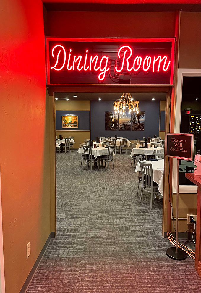 The neon "Dining Room" sign glows like a beacon, guiding hungry travelers to their white-tablecloth destination.