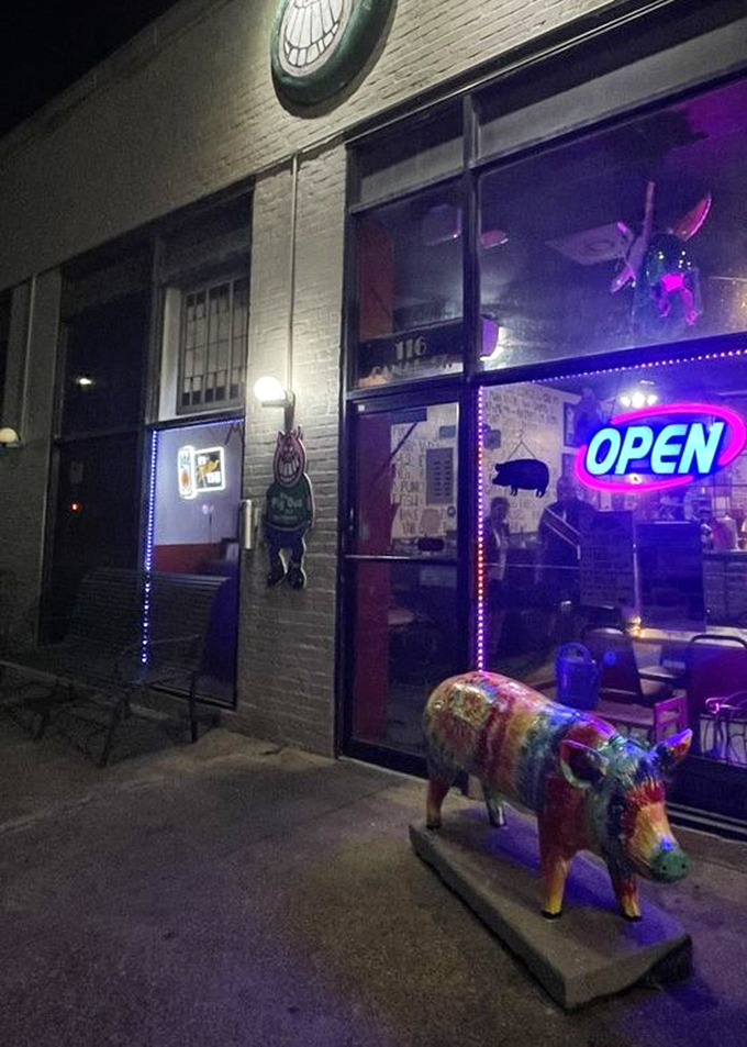 At night, the neon glow transforms this barbecue joint into a beacon of hope for the hungry, with a colorful pig sculpture standing sentinel.