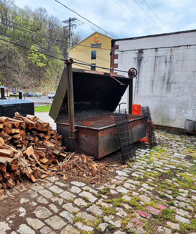 Where the magic happens: the massive smoker with its pile of seasoned wood standing ready for the next batch of meaty masterpieces.