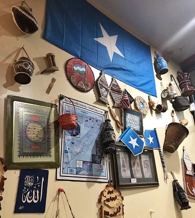 The Somali flag and cultural artifacts create a mini-museum on the wall. Each item tells part of the story behind the food.