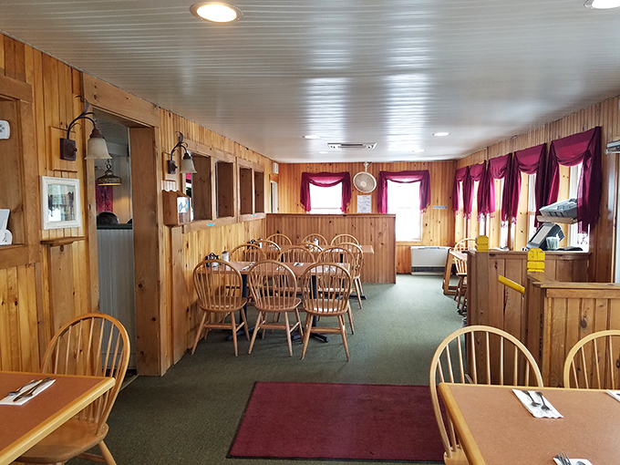 The dining room's warm wood paneling and burgundy valances create an atmosphere that says "stay awhile." Maine hospitality in architectural form.