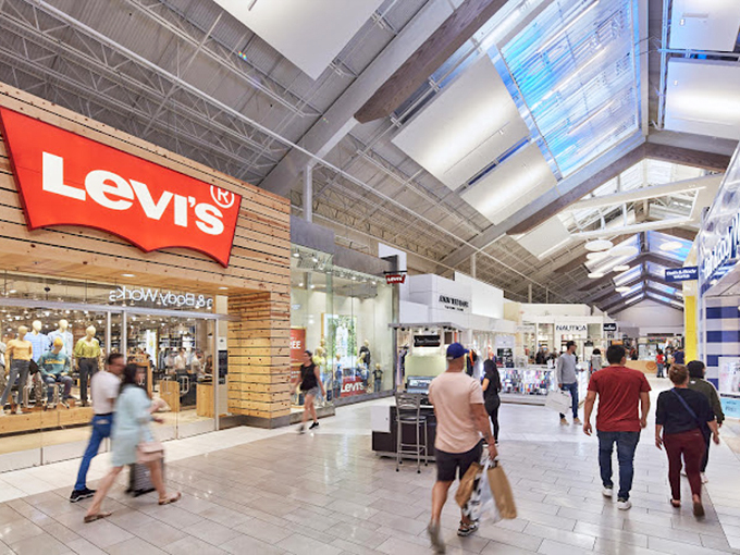 The Levi's store anchors this bright, airy corridor where natural light streams through skylights, creating the perfect illumination for denim decisions.