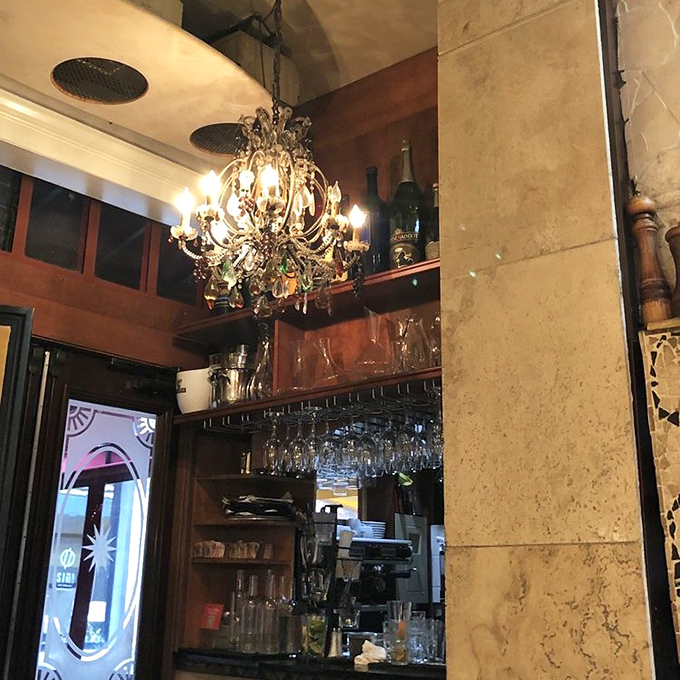The bar area glows with promise, bottles standing like soldiers ready for duty. That chandelier has witnessed countless toasts to la bella vita.