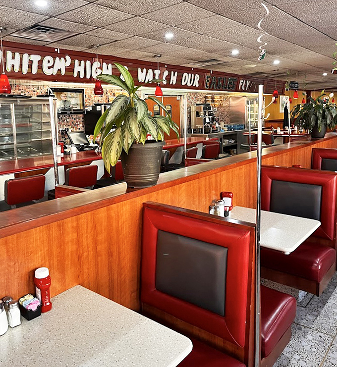 Red booths and wood dividers create the perfect semi-private dining experience. That "Hit 'em High" Eagles sign says you're definitely in Philly.