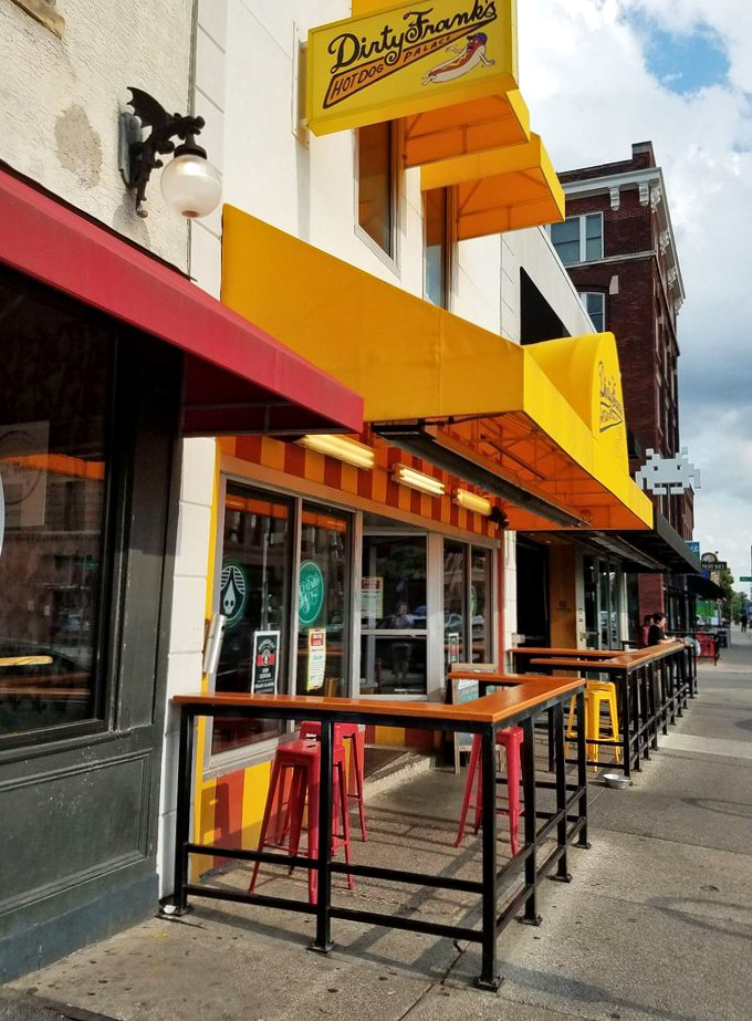 Sidewalk dining with that signature yellow pop. Like sitting in a slice of sunshine while the world hustles by with hot dog envy.