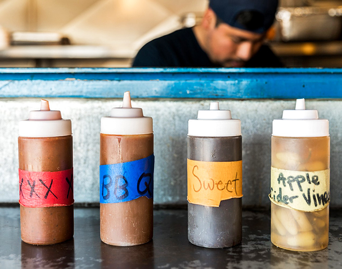 Barbecue sauce bottles lined up like soldiers ready for duty. Each one holds a different path to flavor nirvana &ndash; choose wisely, though they're all winning tickets in this sauce lottery.