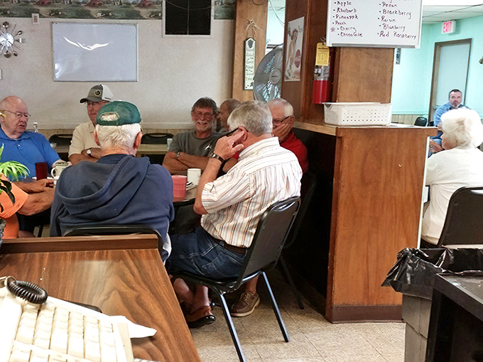The morning crew of regulars, gathered like a small parliament of local wisdom around steaming mugs of coffee.
