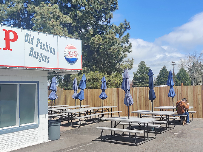 Blue umbrellas and picnic tables create the perfect outdoor dining room where strangers become temporary friends united by great burgers.