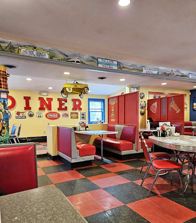 Red booths cradle conversations while the model car overhead keeps watch. This isn't just interior design&mdash;it's a hug in architectural form.