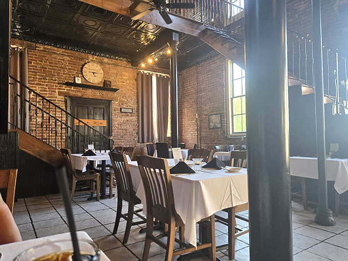 Tables spaced for privacy but close enough for community&mdash;where white tablecloths meet rustic brick in a dance of refined comfort.