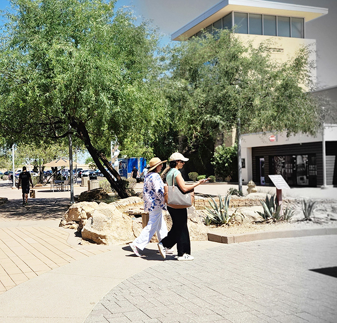 Two shoppers stroll past natural shade, proving that even outlet malls can offer moments of peaceful, pleasant wandering between purchases.