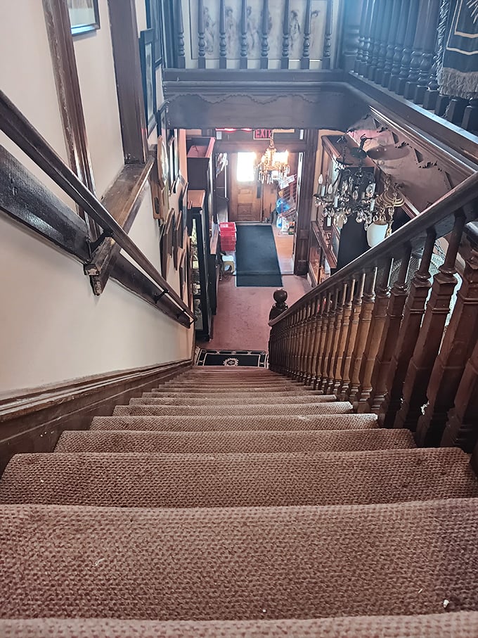 The grand staircase descends into wonderland, its wooden banister polished by thousands of hands all searching for that perfect piece of the past.