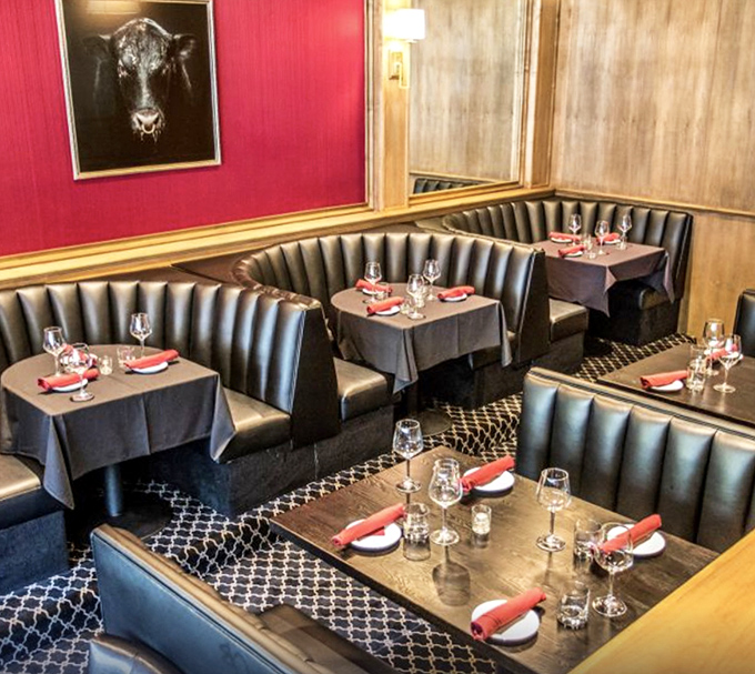 Red walls and curved booths create intimate dining spaces where deals are made, anniversaries celebrated, and diet plans temporarily forgotten.