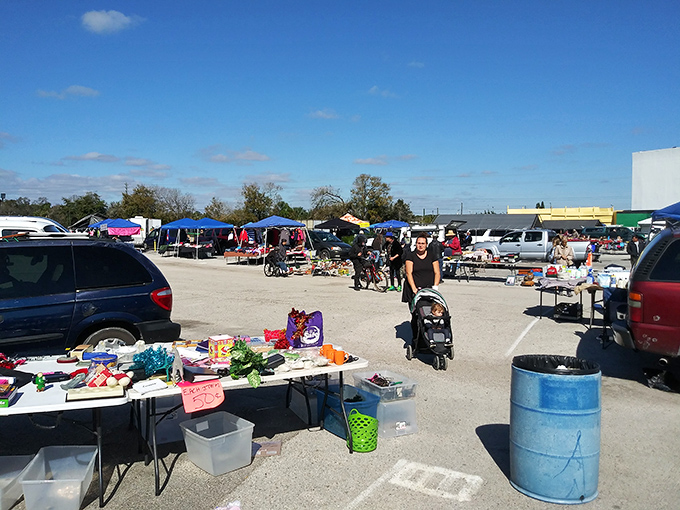The weekend marketplace sprawls across the pavement, where tables loaded with everyday treasures create a temporary retail city.