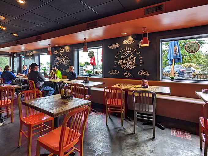 Rustic wooden tables bathed in natural light, with burger diagrams on the walls serving as both art and helpful eating instructions.