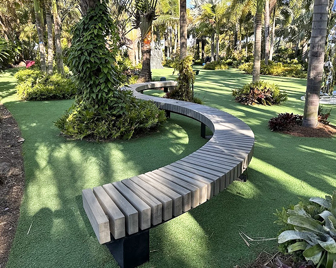 The curved wooden bench isn't merely functional—it's a sculptural element that guides visitors through the landscape like a gentle, artistic river.