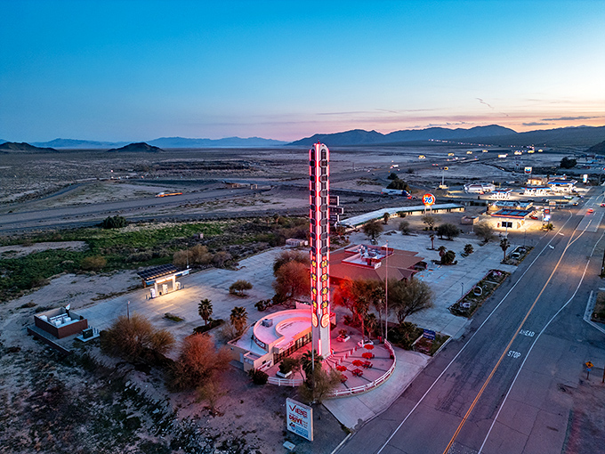 At sunset, the World's Largest Thermometer glows against the desert sky, a beacon for road-weary travelers.