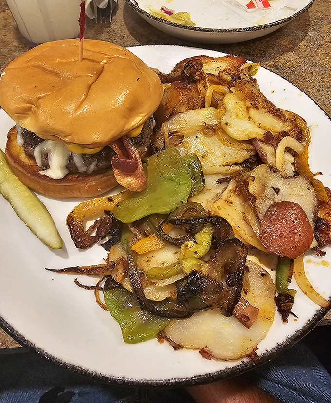 A burger that requires jaw-unhinging preparation, with a side of home fries that look like they've been gossiping with onions and peppers all morning.
