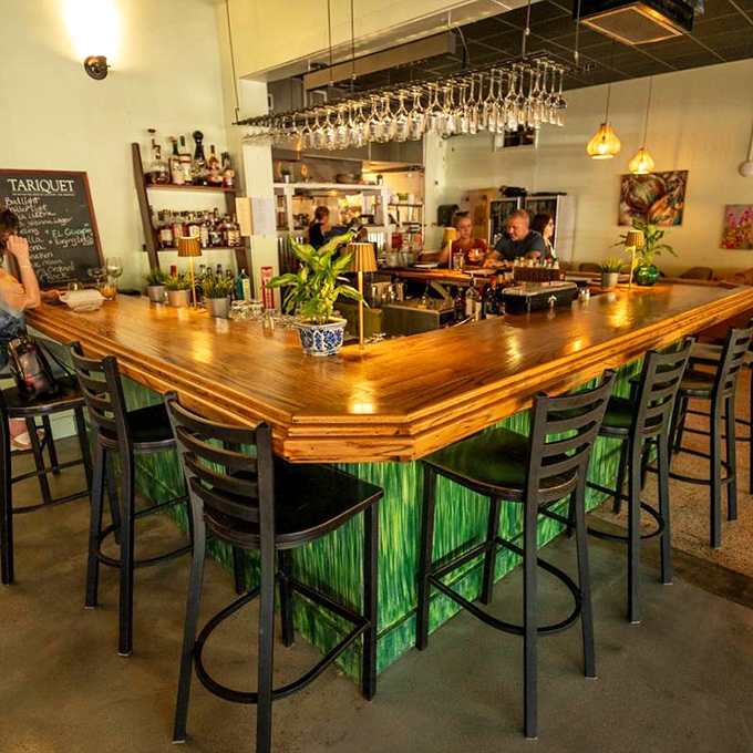 The bar's distinctive green glow isn't just on-brand&mdash;it creates an almost underwater ambiance perfect for a seafood-focused restaurant.