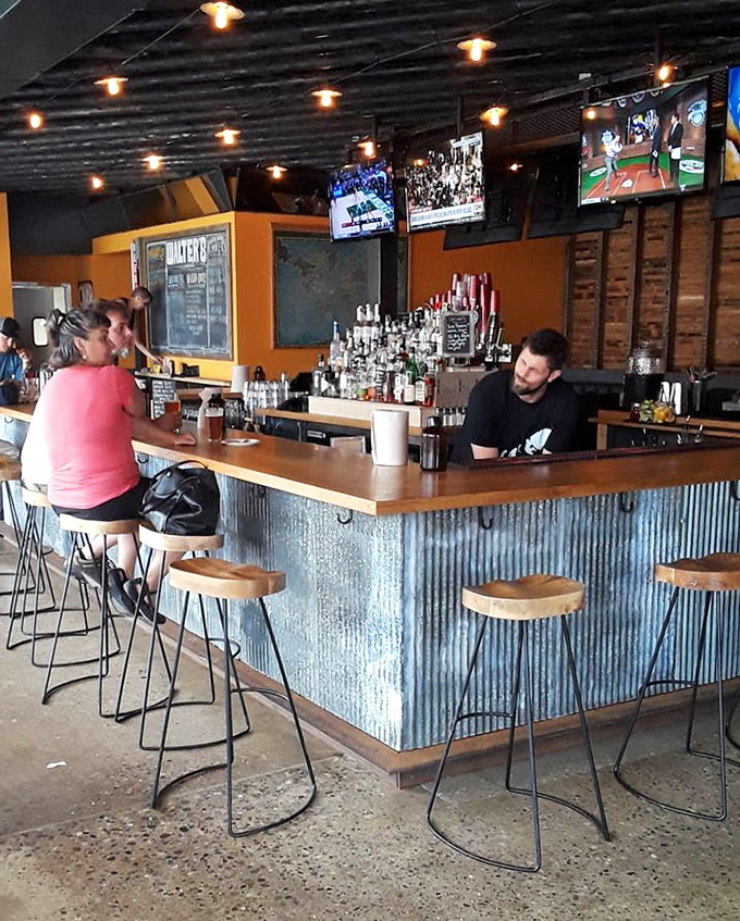 The corrugated metal bar wraps around to create a communal space where strangers become friends over shared appreciation of smoked perfection.