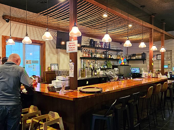 Bamboo elements overhead create a canopy effect above the polished bar, where liquid magic happens one carefully crafted drink at a time.