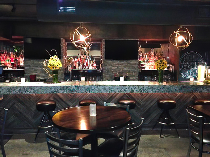 The bar's herringbone wood paneling and spherical lighting fixtures create an atmosphere that's equal parts rustic and sophisticated.