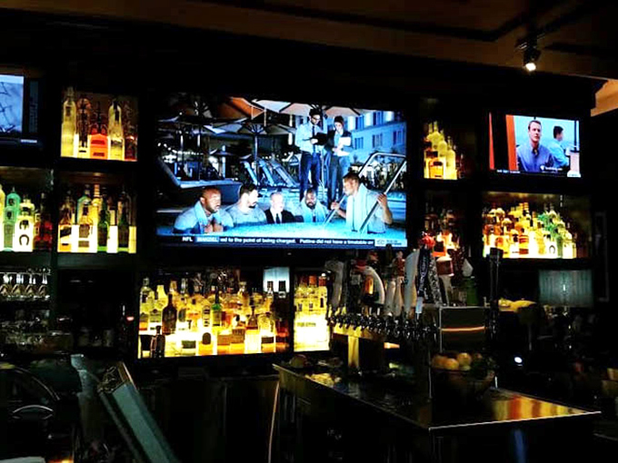 The backlit bottles create a warm glow that says, "Your Manhattan will be excellent, and so will the company."