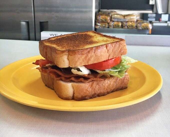 A BLT that understands the importance of proper architecture – crisp bacon, fresh lettuce, and ripe tomato between perfectly toasted bread on a sunny plate.