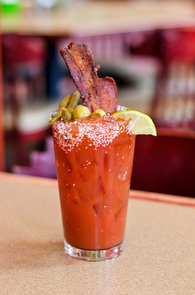 The Bloody Mary arrives with a bacon antenna and enough garnishes to qualify as both cocktail and appetizer. Breakfast of champions.