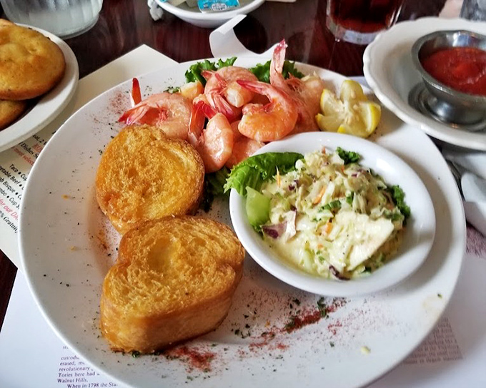 These boiled shrimp aren't just seafood—they're an invitation to slow down and savor each bite alongside what appears to be perfectly executed coleslaw.