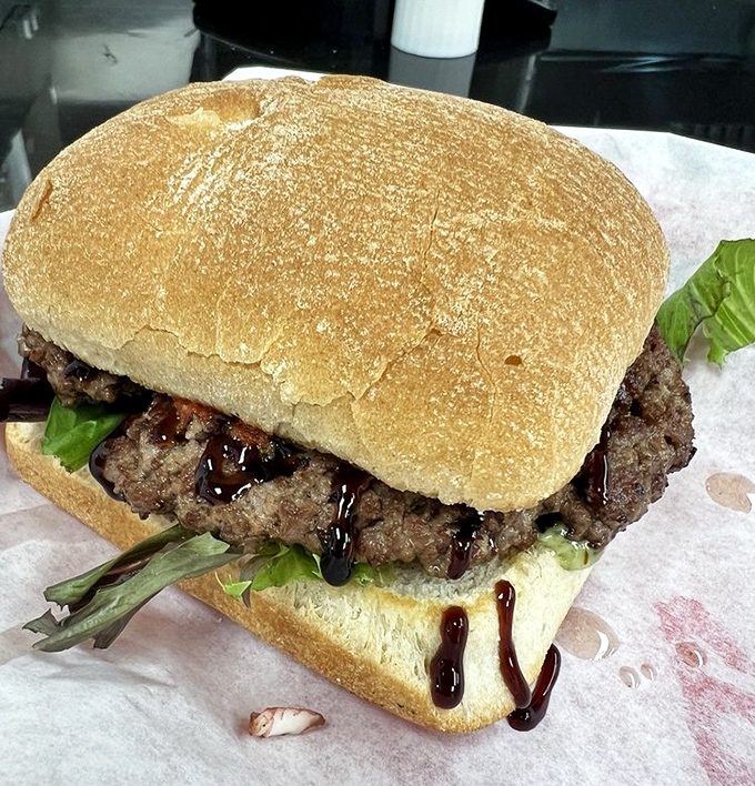 A burger that doesn't hide behind fancy toppings&mdash;just honest beef, fresh greens, and a drizzle of sauce. Simplicity at its finest.