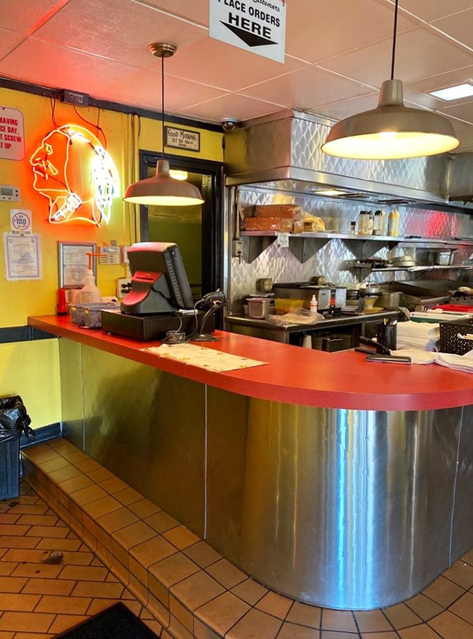 The stainless steel counter gleams under neon lights&mdash;a silver runway where breakfast dreams taxi before taking flight to your table.