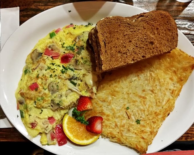 A crab omelet that's having an identity crisis as a work of art. Those fresh strawberries and hash browns aren't just sides – they're supporting characters in a delicious story.