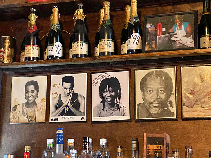 The wall of fame showcases visitors who came for the food and left as family. Those champagne bottles mark celebrations shared within these walls.