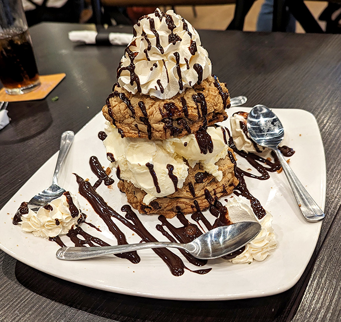 This towering dessert isn't just served—it's presented. Whipped cream, chocolate drizzle, and cookie layers create an edible skyscraper of joy.